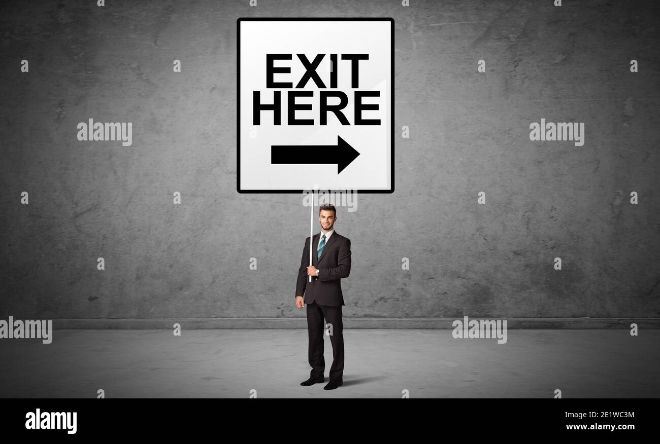 business person holding a traffic sign with EXIT HERE inscription, new ...