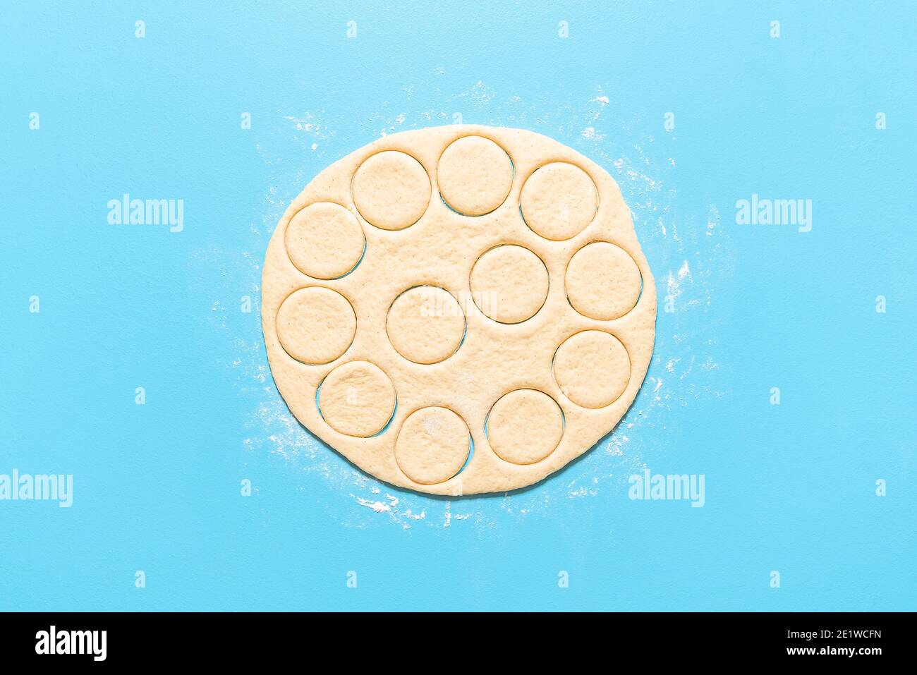 Cooking doughnuts, raw donut dough cut in round shapes, on blue ...