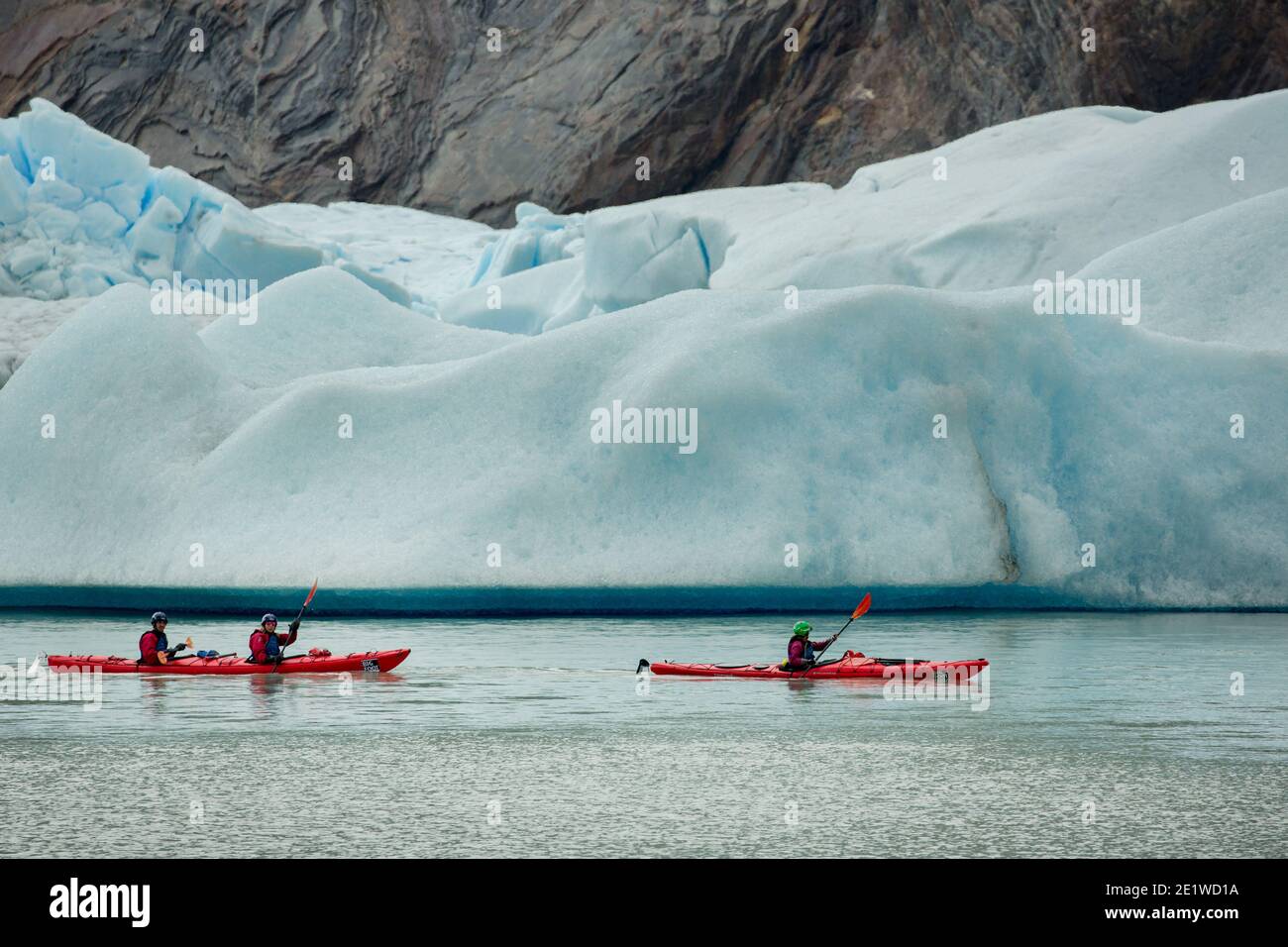 Tourists in red kayaks paddle on Lago Grey beside icebergs calved from ...