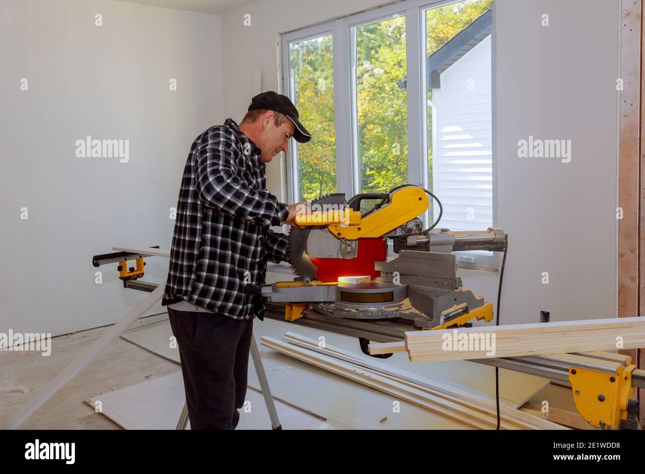 Builder uses circular saw tool to cut wood baseboard woodwork equipment ...