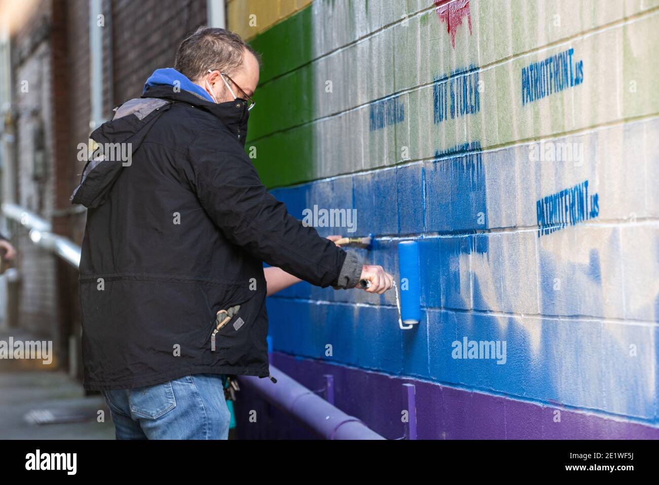 Community member repaints a mural which was defaced with white ...