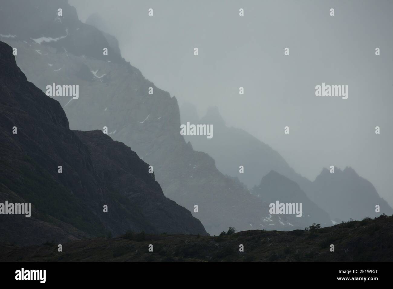 Jagged and sharp ridges of snow-streaked rock emerge from the mist at ...