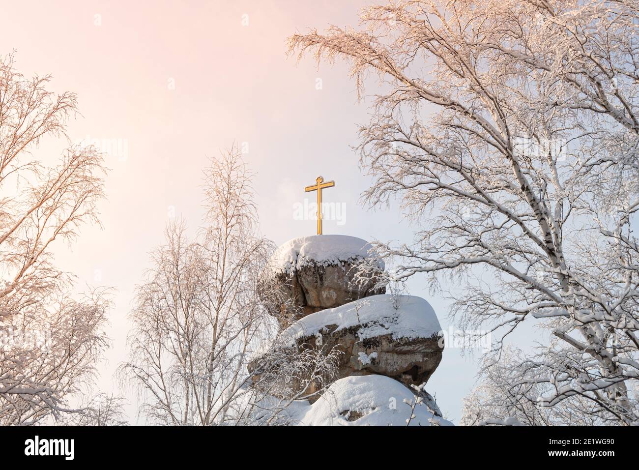 Christian cross on rock in winter forest. Golden cross on stone with ...