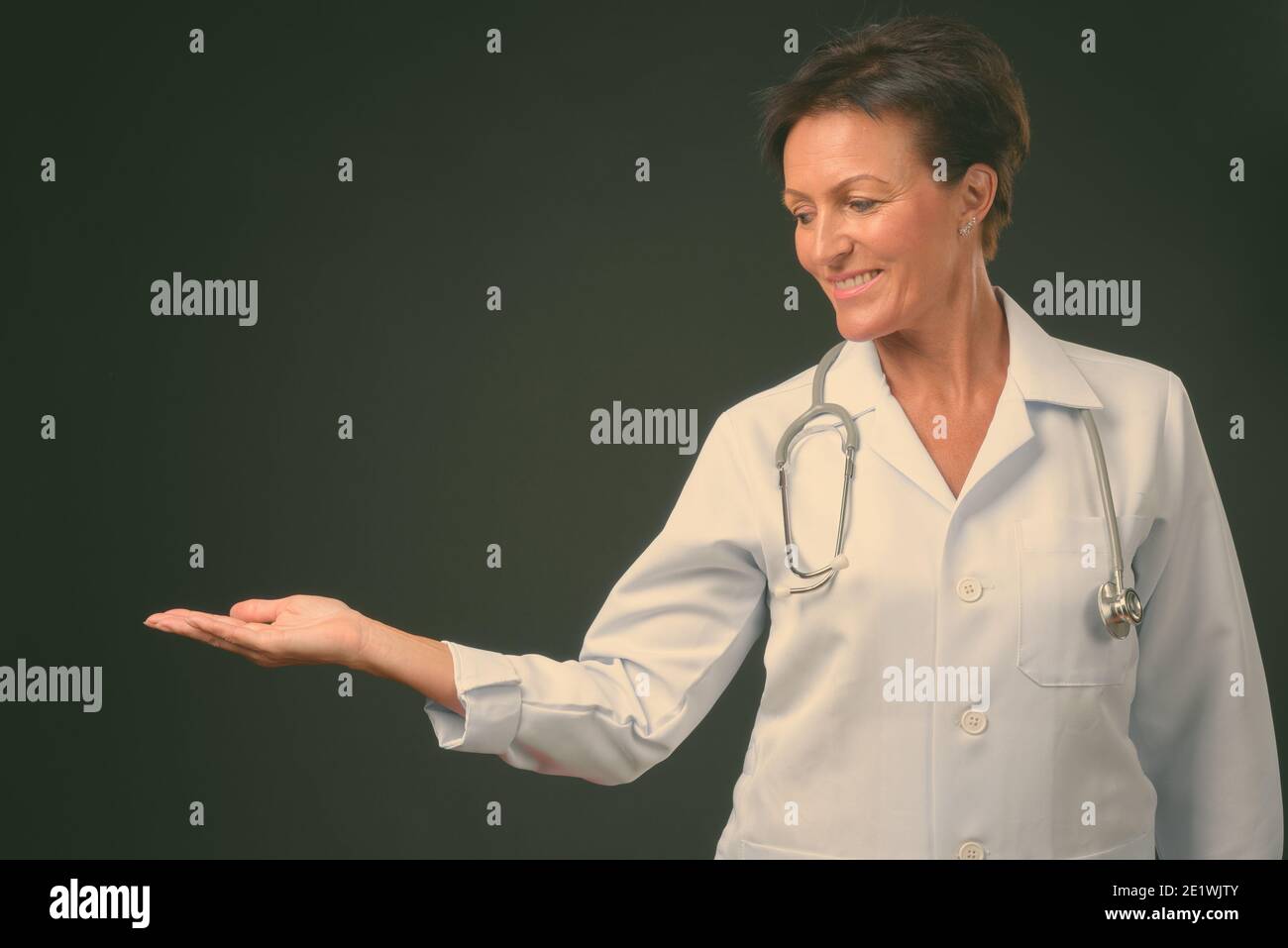 Mature beautiful woman doctor with short hair against black background ...
