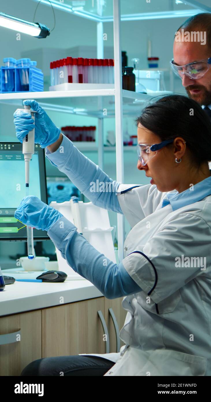 Scientist woman pipetting liquid to test tube working in equipped lab ...