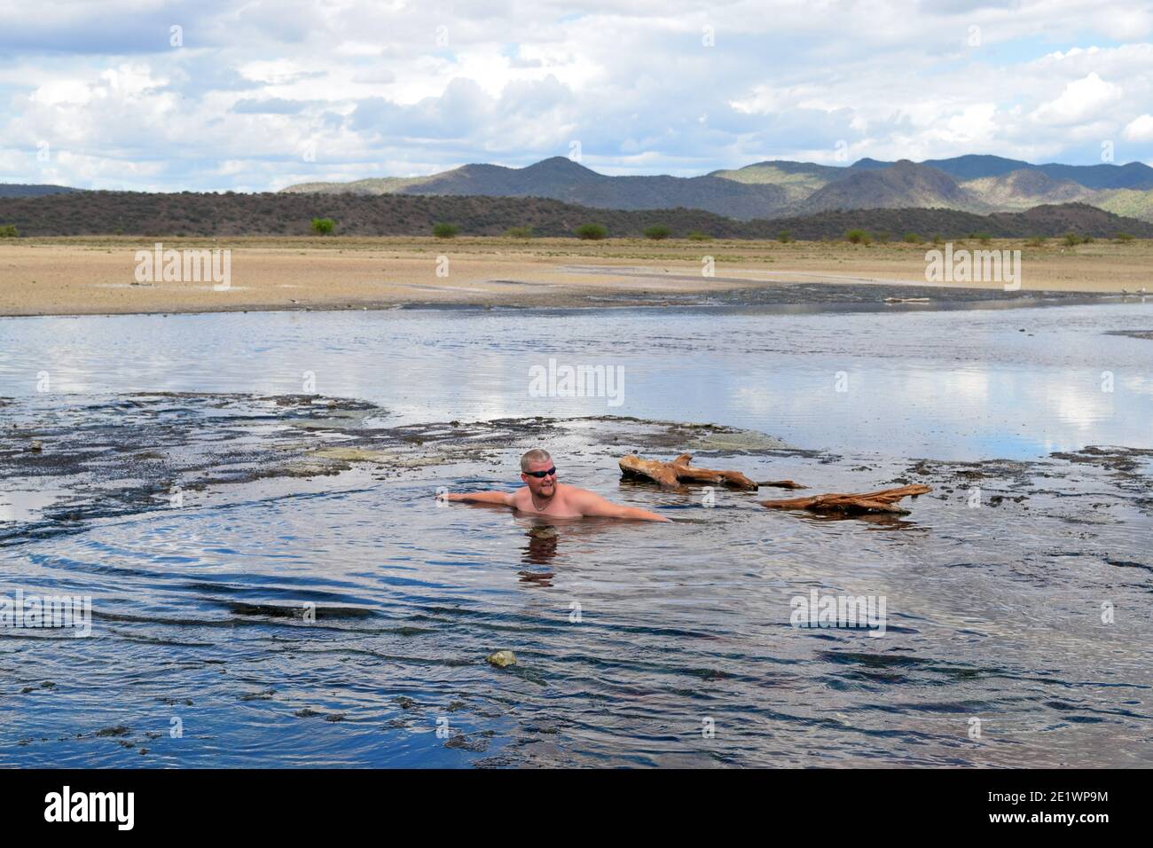 Front view of a shirtless man swimming in a hot spring at Lake Magadi ...