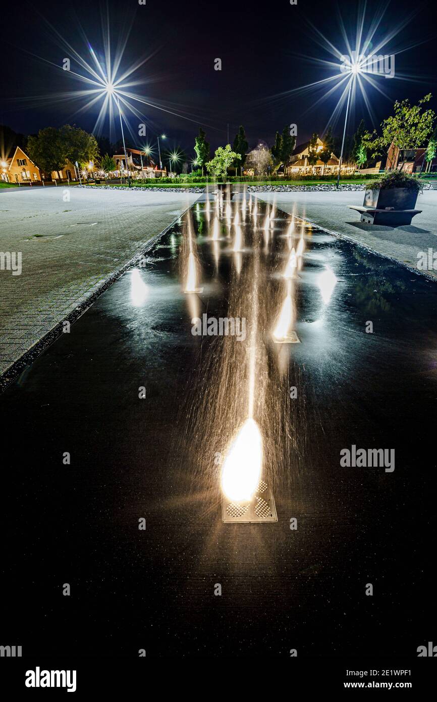 Multiple jets of water in a fountain, lighting show on ground in night ...
