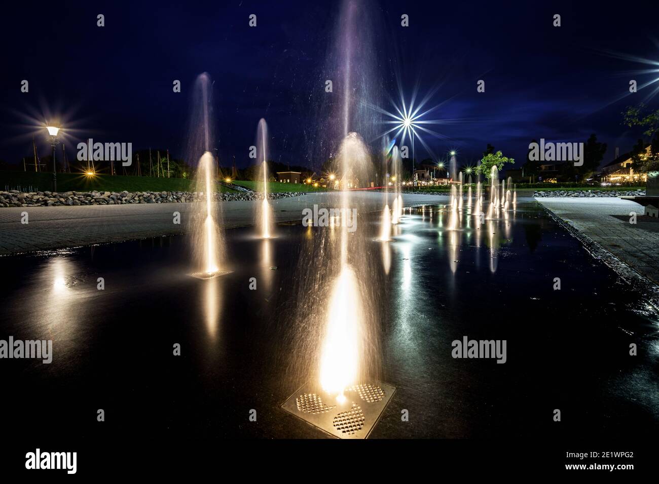 Multiple jets of water in a fountain, lighting show on ground in night ...