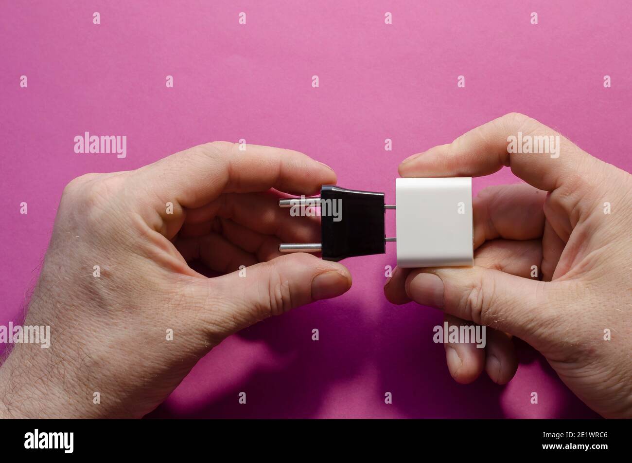 AC and DC adapters in men's hands. The male connects the black wall ...