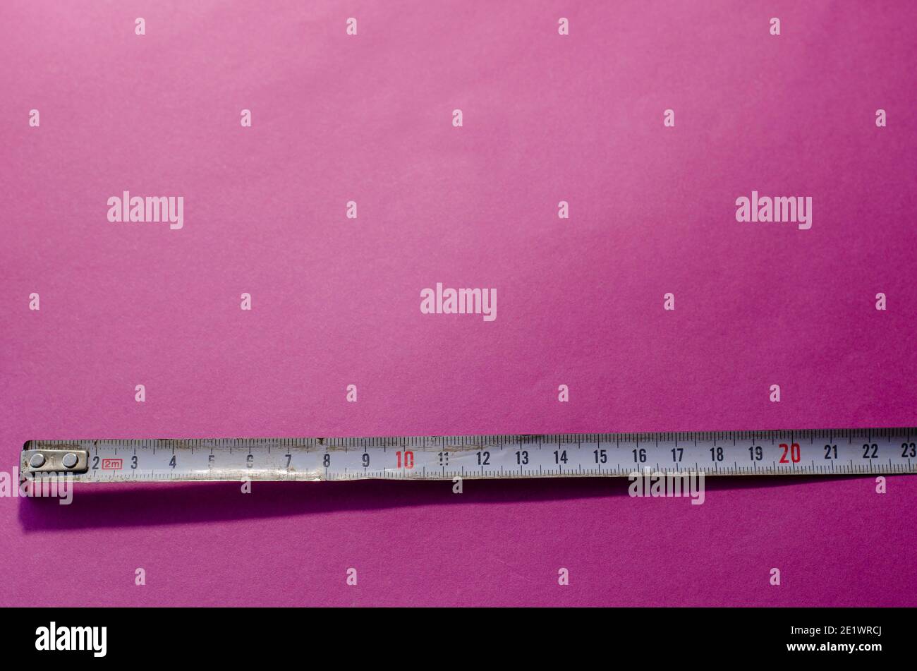 An old metal measuring tape on pink background. Fragment of the ...