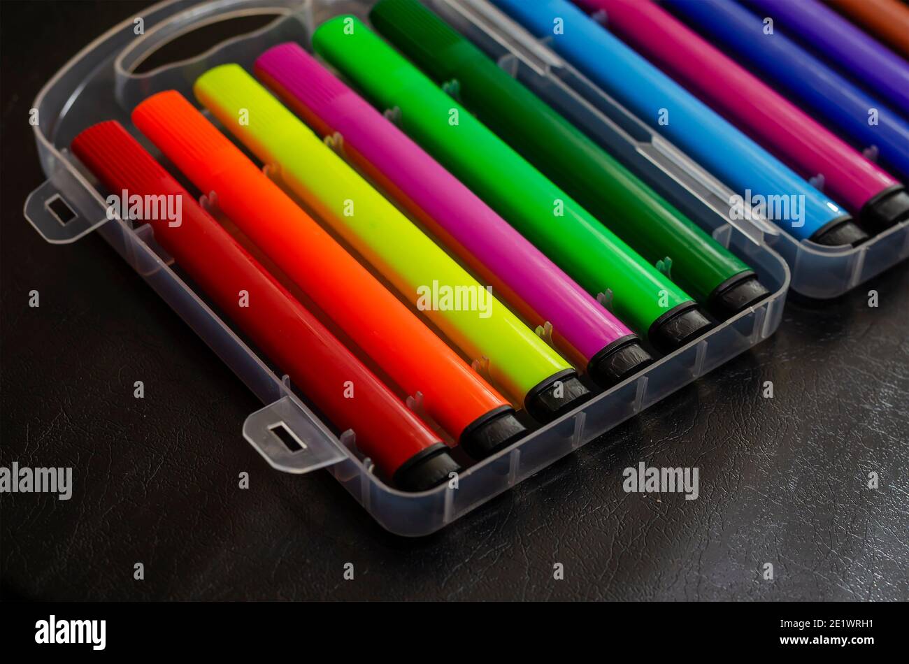 Set of colored felt-tip pens in plastic container on black table ...