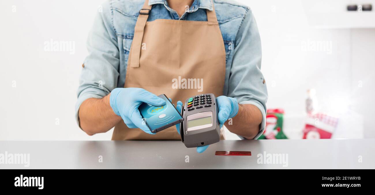 Cashier hand holding credit card reader machine and wearing disposable ...