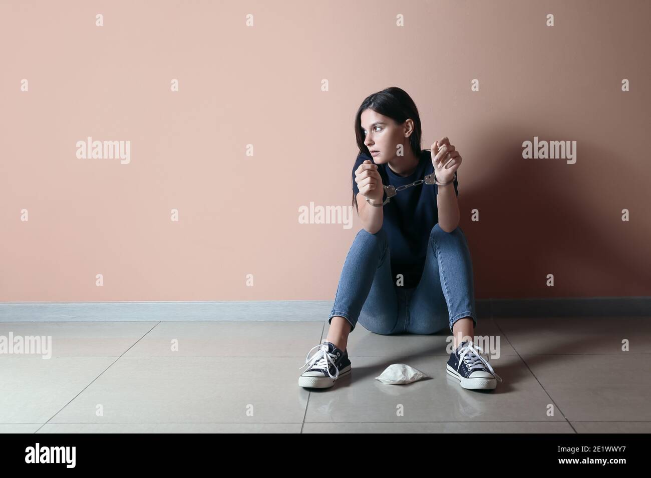 Female junkie sitting near color wall Stock Photo - Alamy