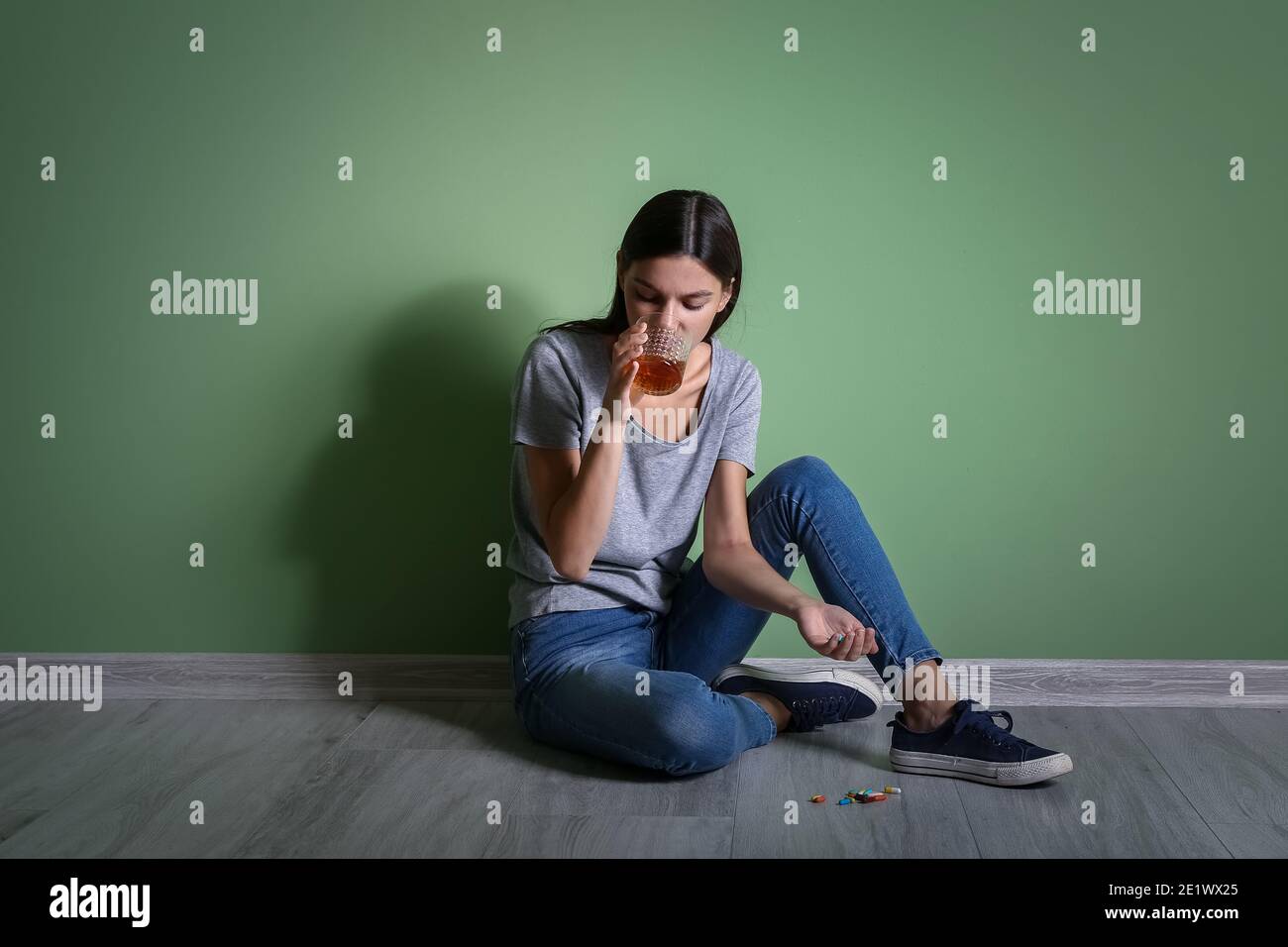 Female junkie with drugs and alcohol near color wall Stock Photo - Alamy