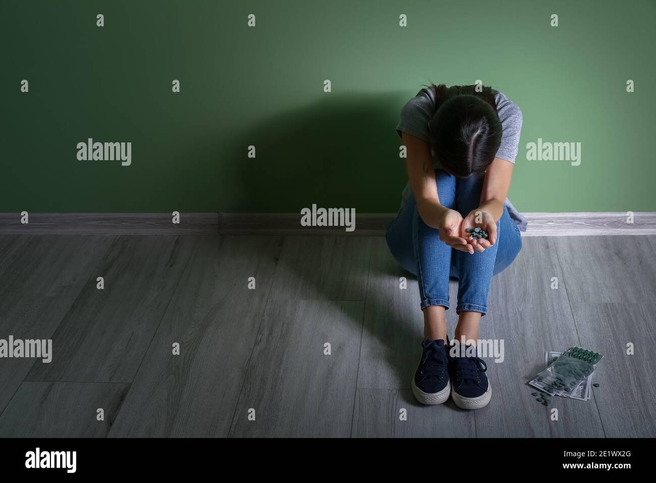 Female junkie sitting near color wall Stock Photo - Alamy