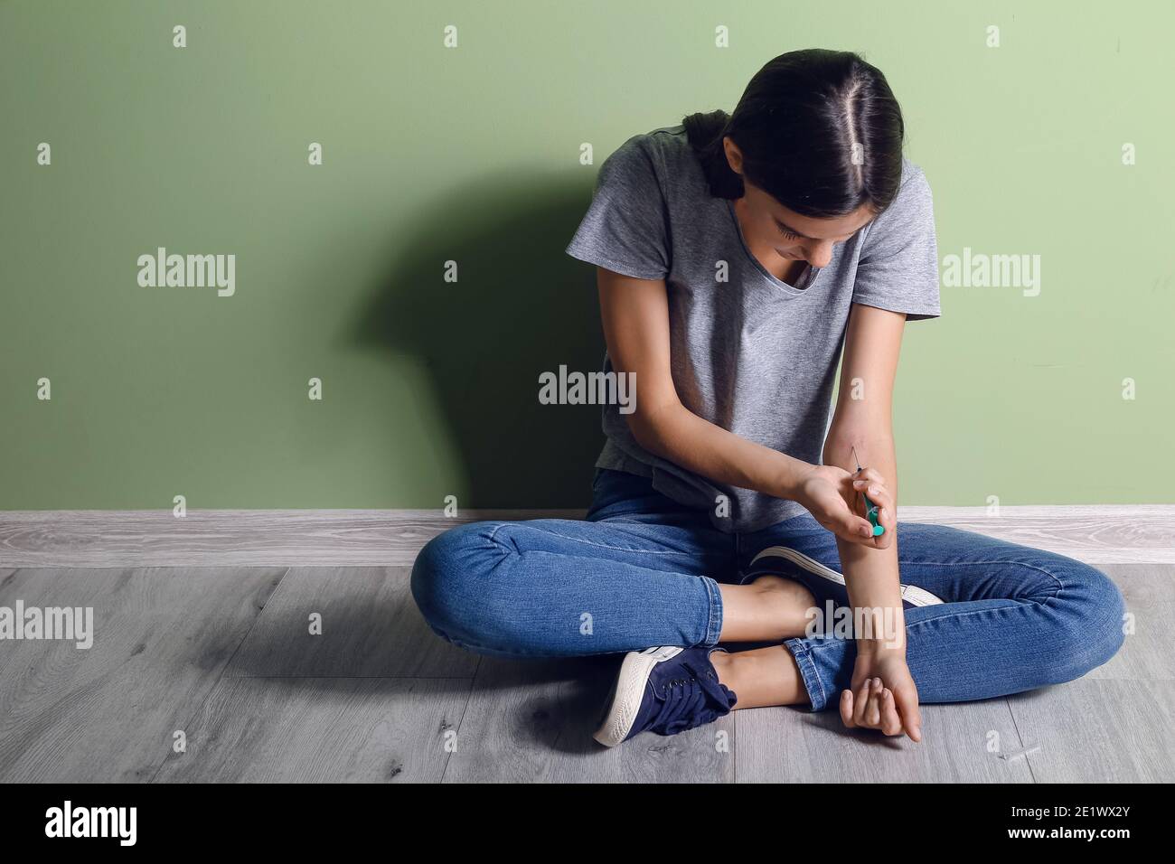 Female junkie giving herself injection while sitting on floor Stock ...