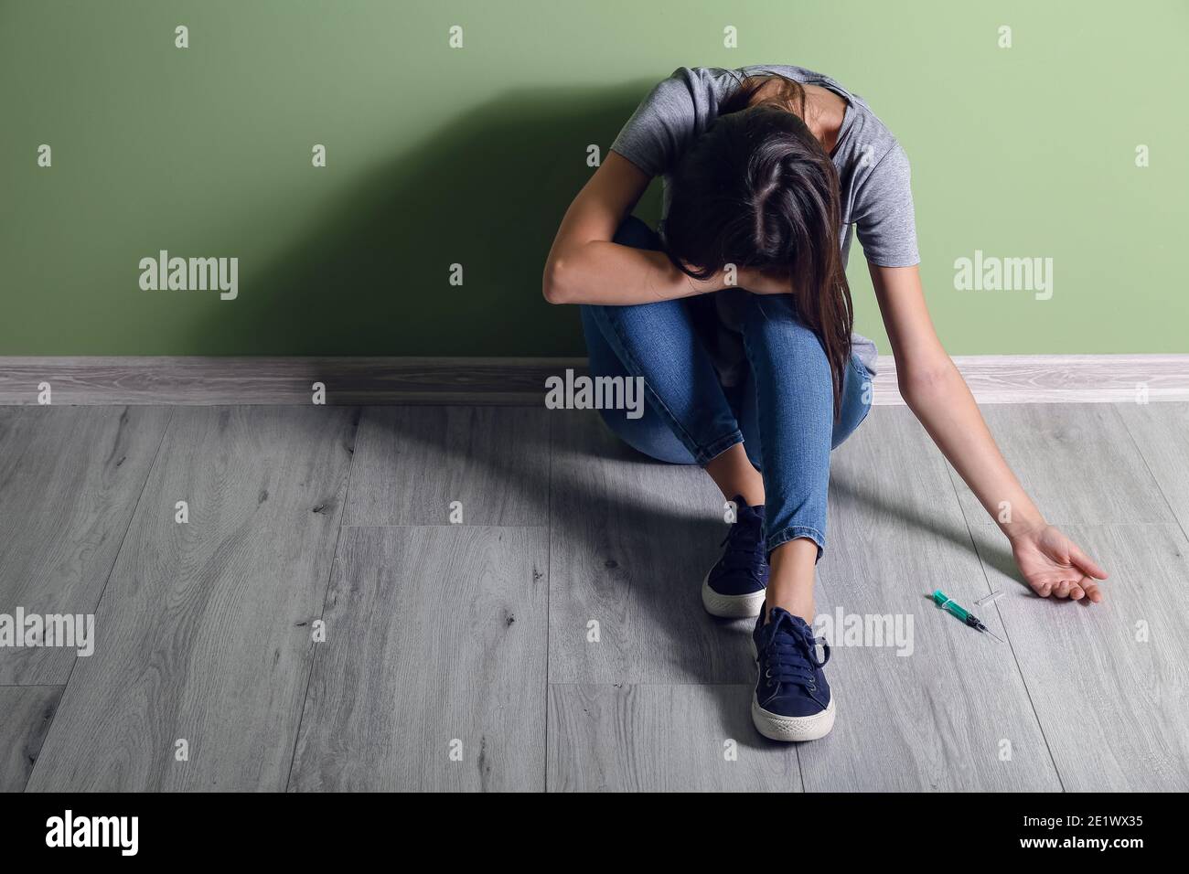 Female junkie sitting near color wall Stock Photo - Alamy