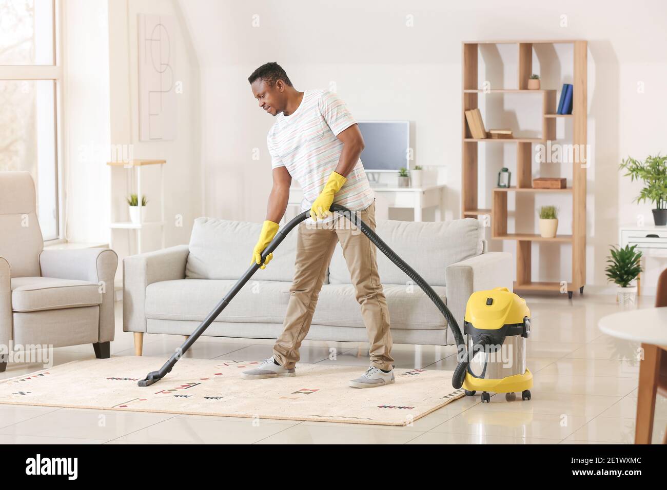 African-American man hoovering his flat Stock Photo - Alamy