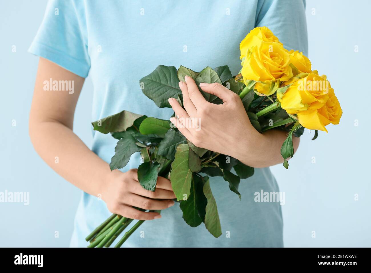 Woman with bouquet of beautiful yellow roses on color background Stock ...