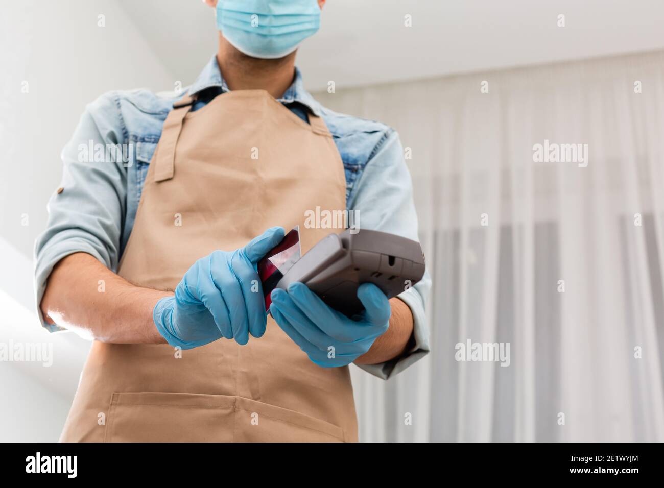 Cashier hand holding credit card reader machine and wearing disposable ...