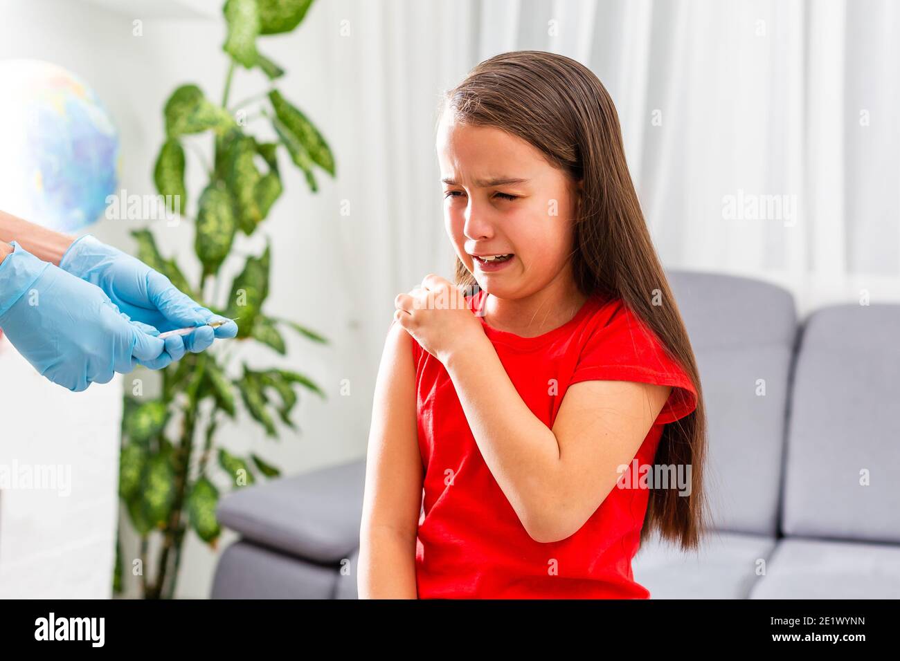 A doctor injects a vaccine to a little girl. The girl is afraid and ...