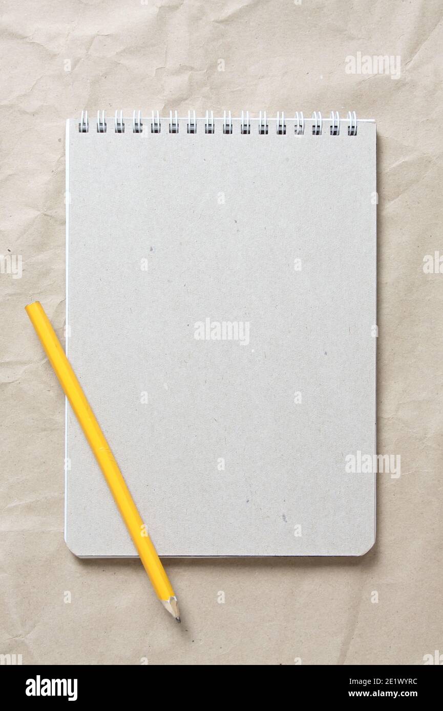 Gray notepad with white coiled spring and pencil on a background of ...