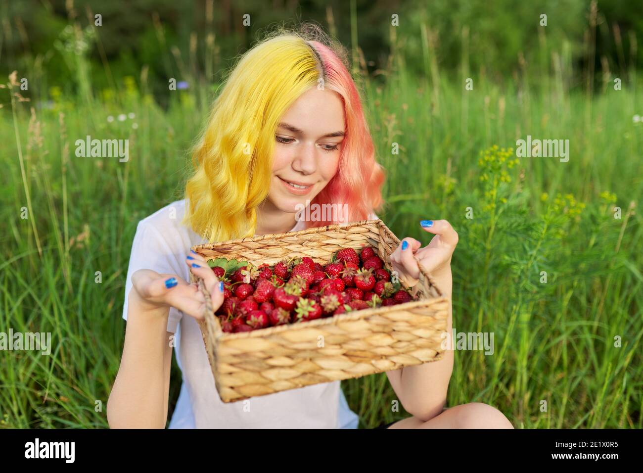 Smiling teen girl with strawberries in basket, garden nature background ...