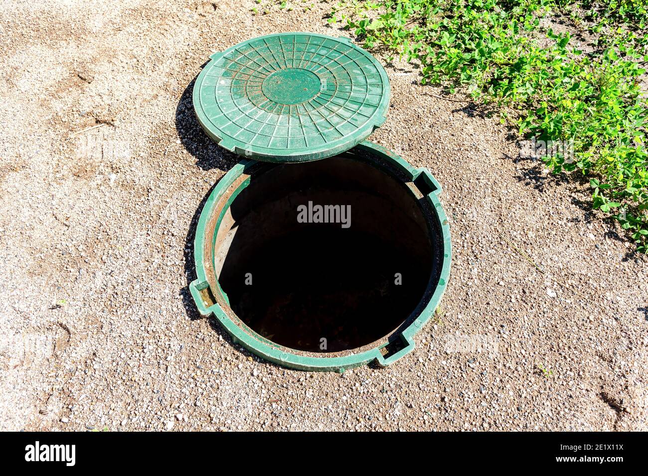 Opened unsecured sewer manhole of rural septic tank with green plastic ...