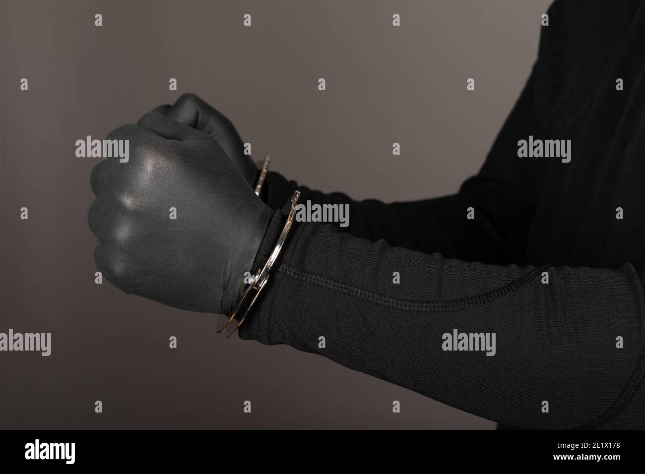 Close up picture of robbers hands with black gloves wearing handcuffs ...