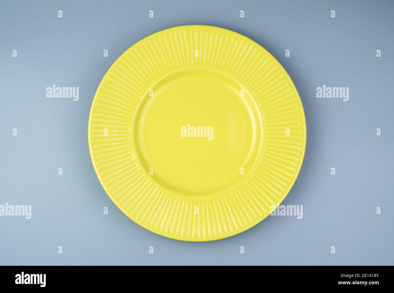 An empty yellow plate on a gray background Stock Photo - Alamy