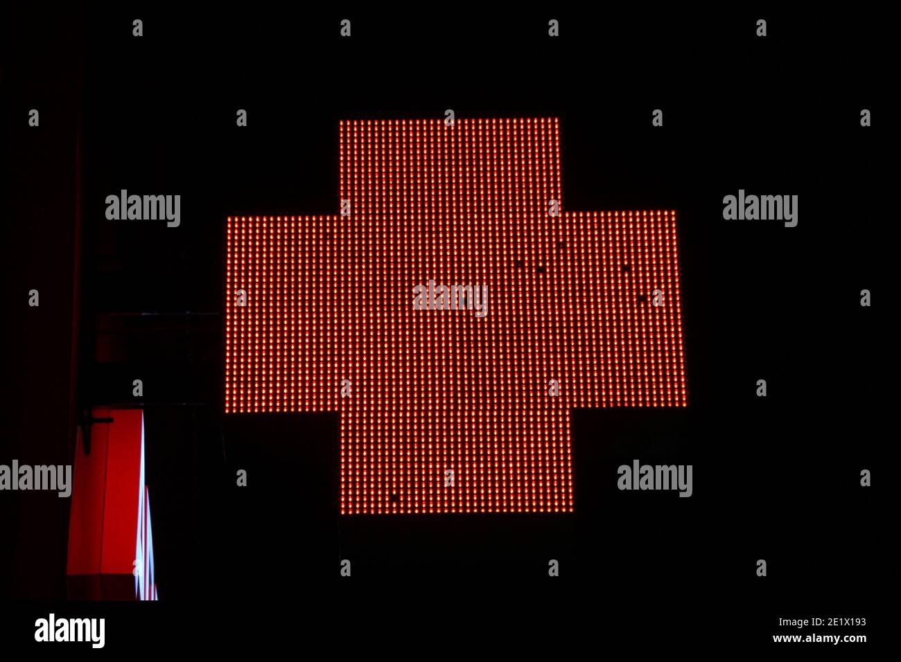 Glowing pixel cross of LED lamps on black background. Red cross symbol ...