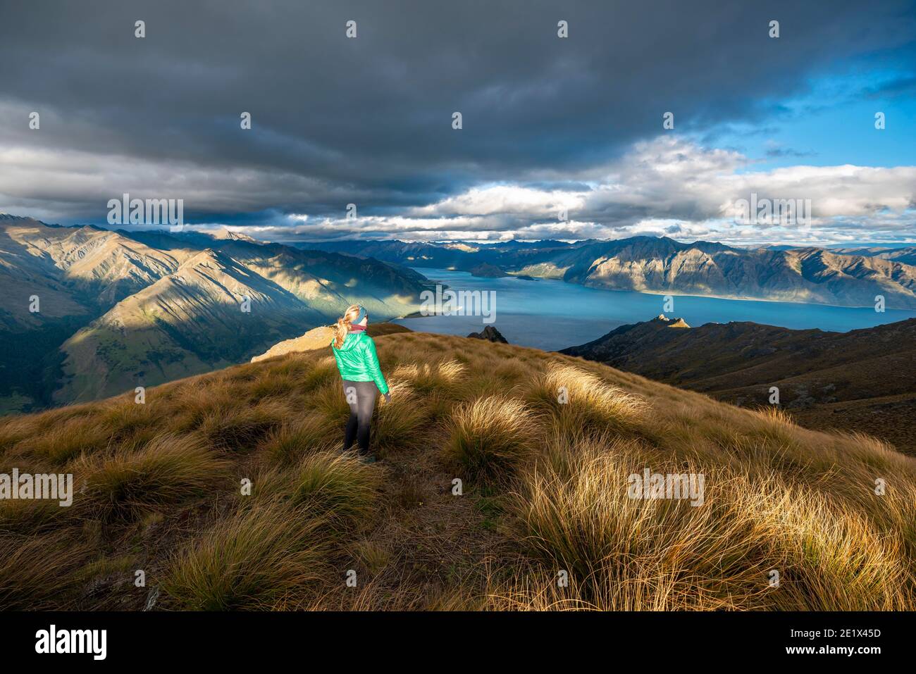Hiker looks into the distance, view of Lake Hawea in the evening light ...