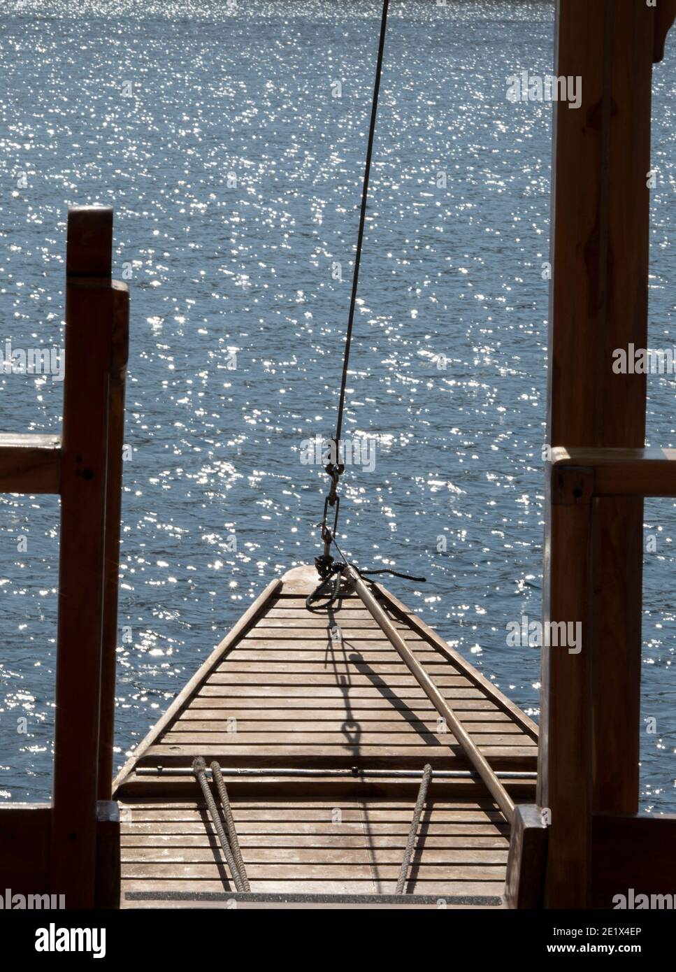 detail of a wooden ship stern sailing towards the sun with sparkling ...