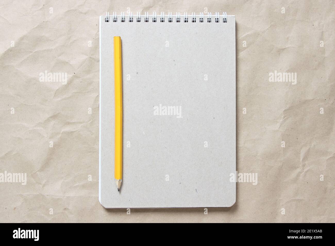 Gray notepad with white coiled spring and pencil on a background of ...