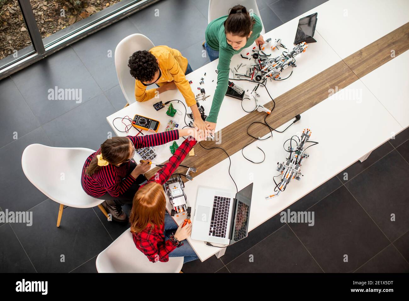 Overhead view at group of happy kids programming electric toys and ...