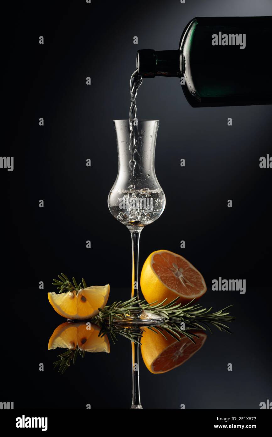 Gin is poured in a small glass from an antique bottle of dark glass. A ...