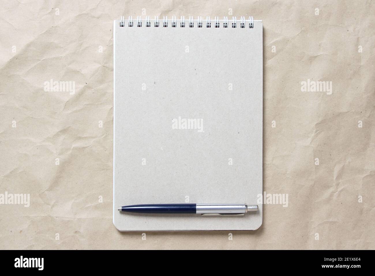 Gray notepad with white coiled spring and pen on a background of beige ...