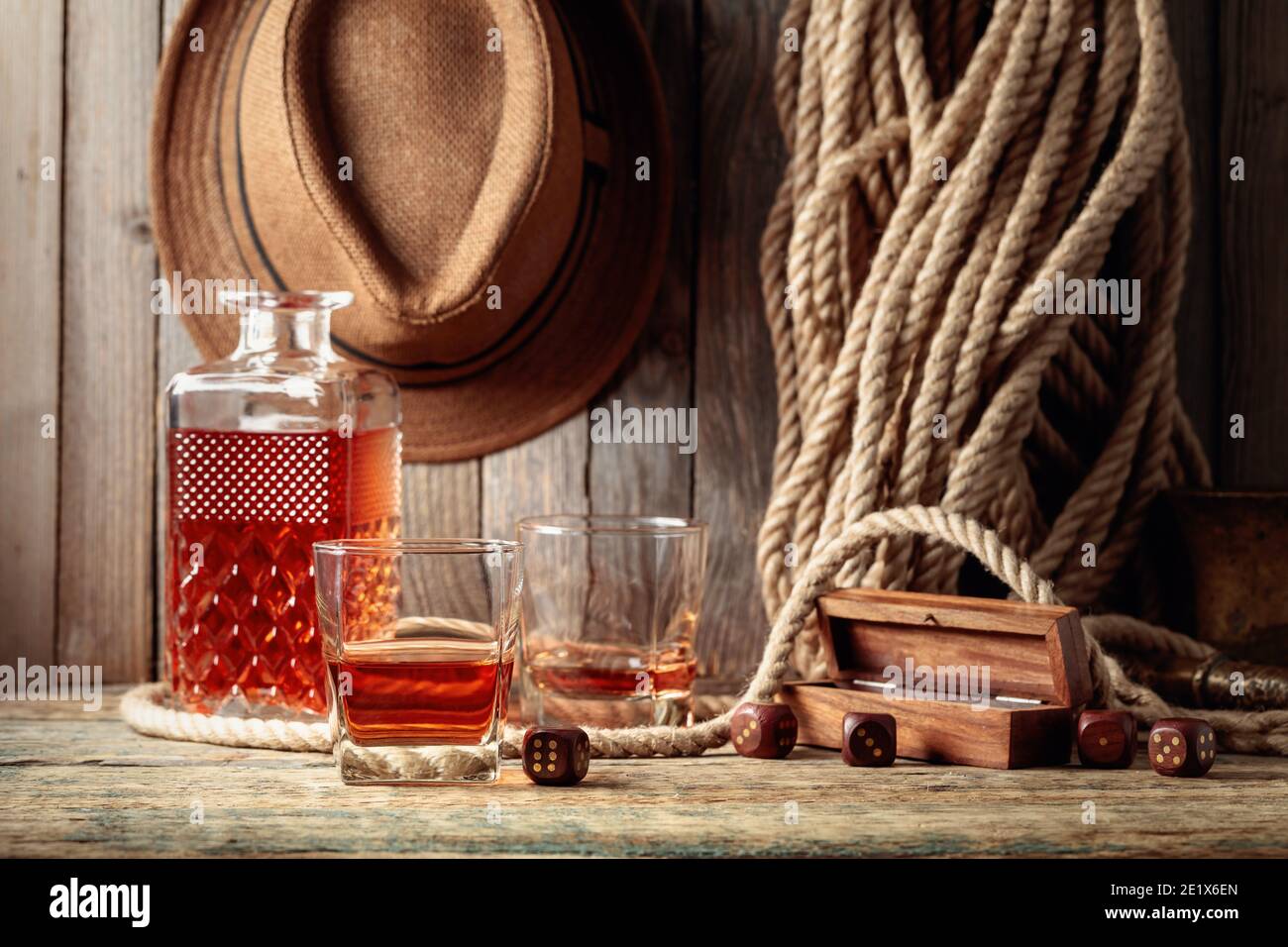 Strong alcoholic drink and dice on an old wooden table. In the ...