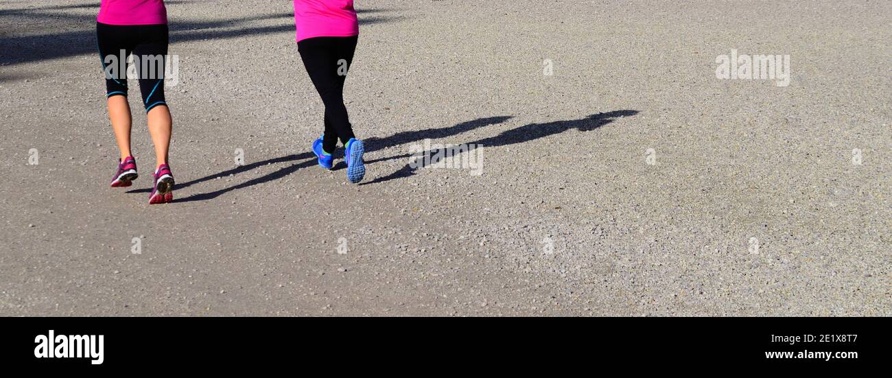 two young athletic women running in the sun panorama view Stock Photo ...