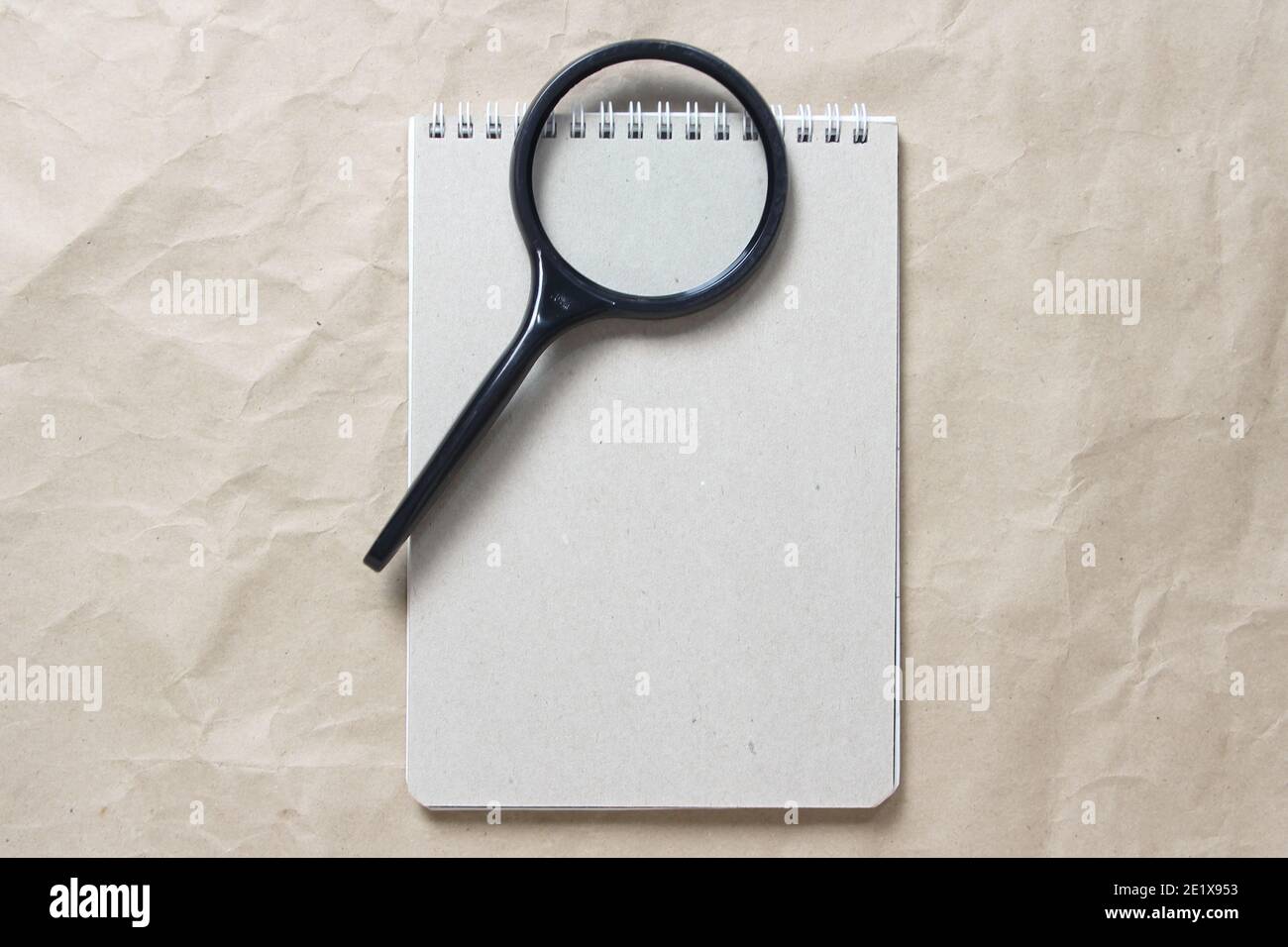 Gray notepad with white coiled spring and magnifier on a background of ...