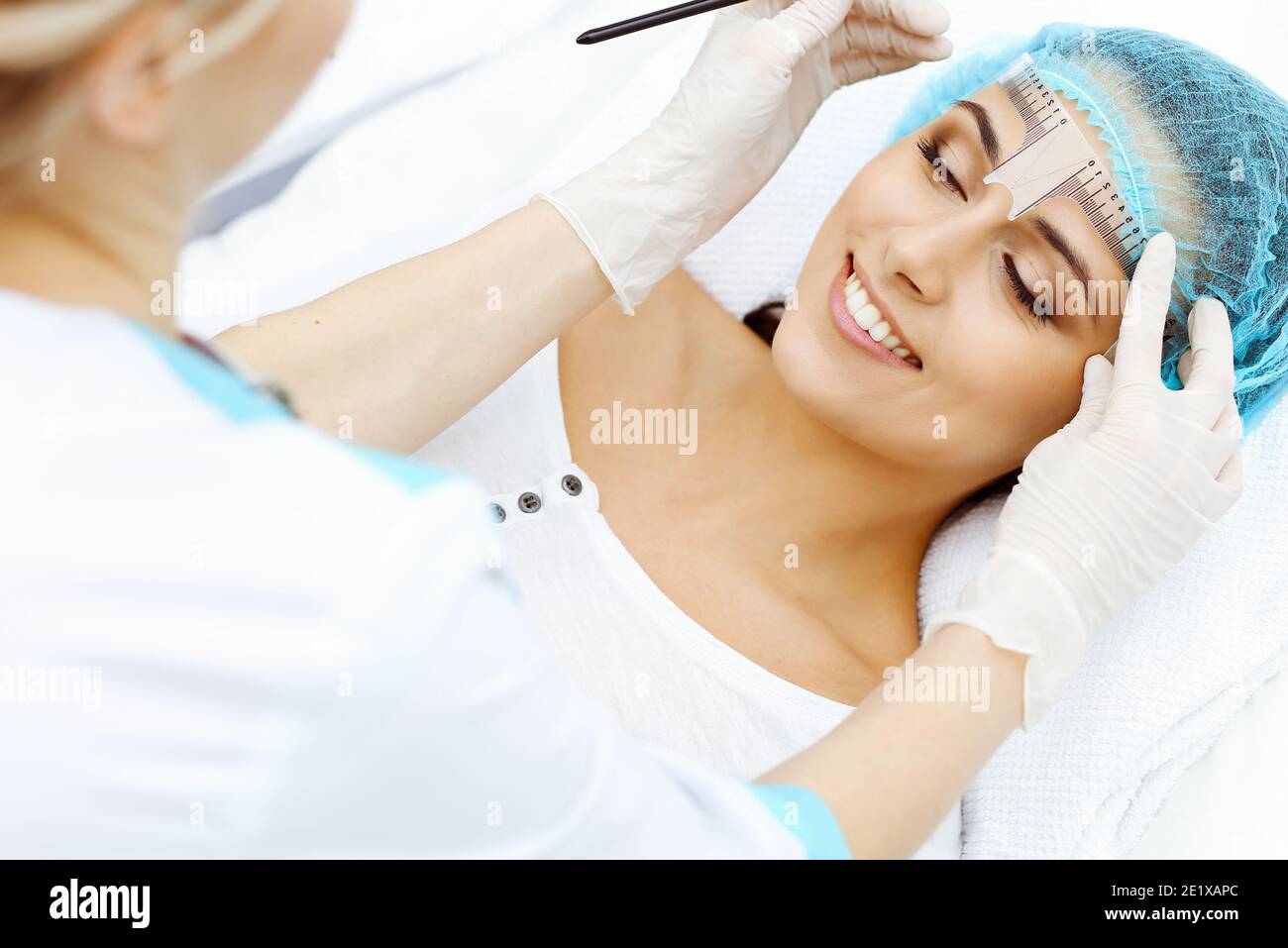 Professional beautician is going to correct eyebrow line at woman face ...