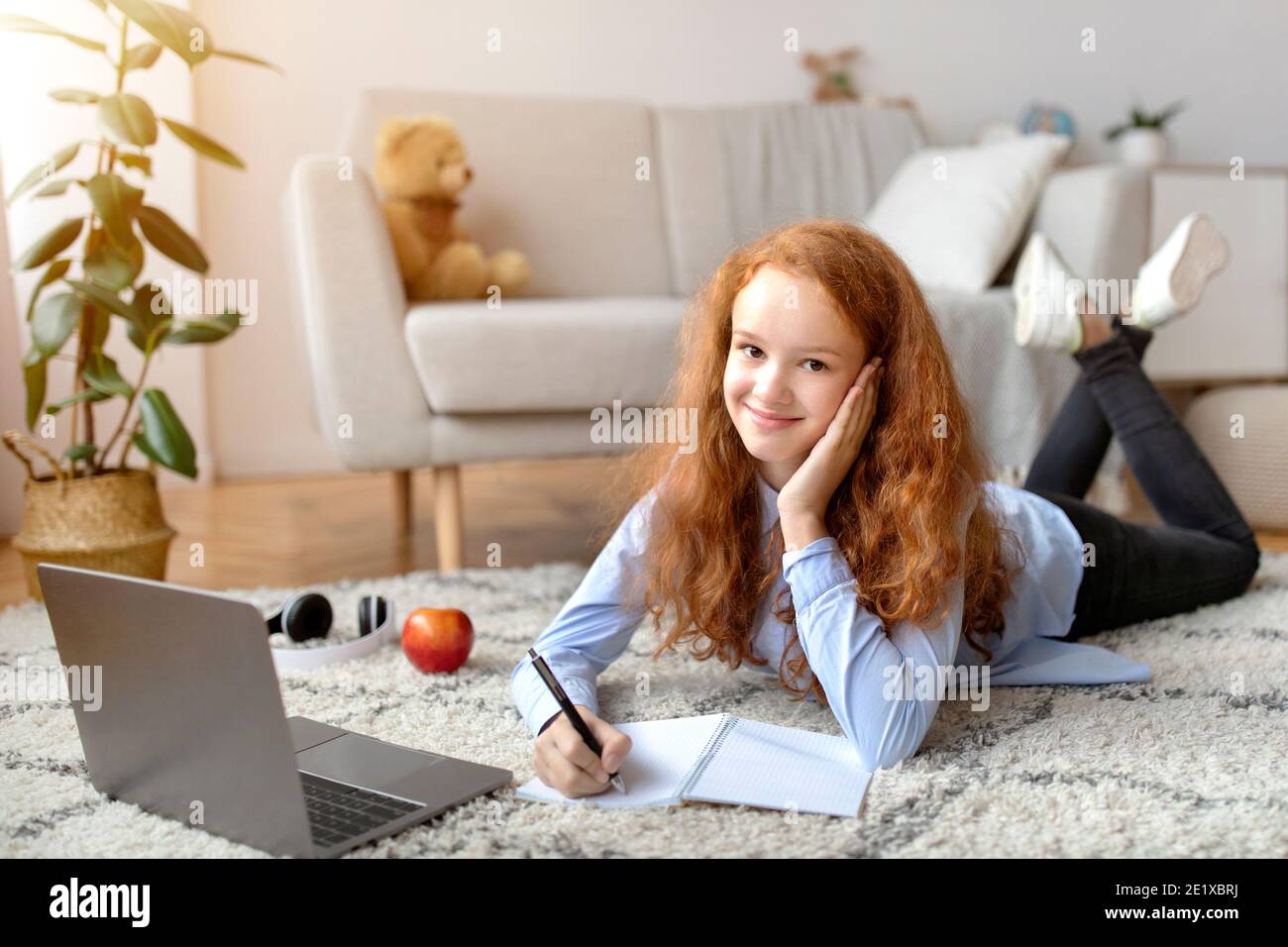 Girl lying on floor, using laptop, writing in notebook Stock Photo - Alamy