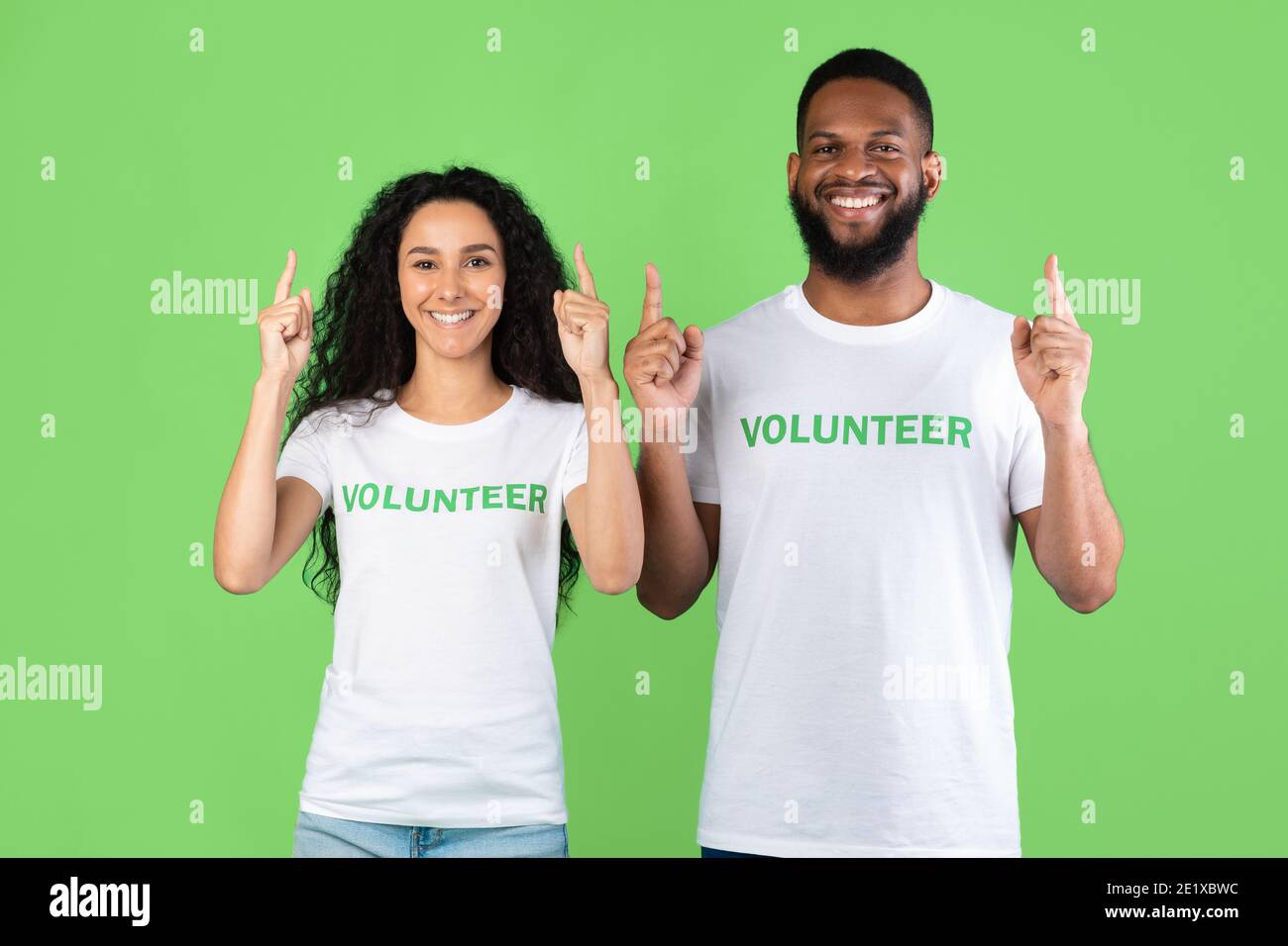Two Multiracial Volunteers Pointing Fingers Up Standing Over Green ...