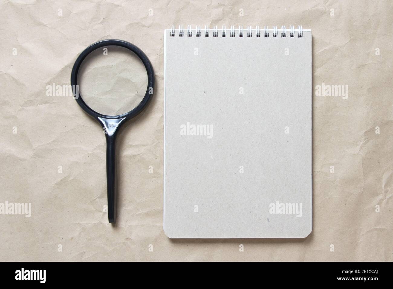 Gray notepad with white coiled spring and magnifier on a background of ...