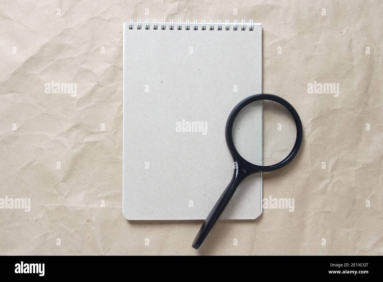 Gray notepad with white coiled spring and magnifier on a background of ...