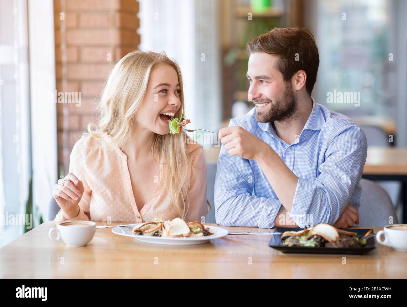 Joyful young couple having lunch together at coffee shop, millennial ...