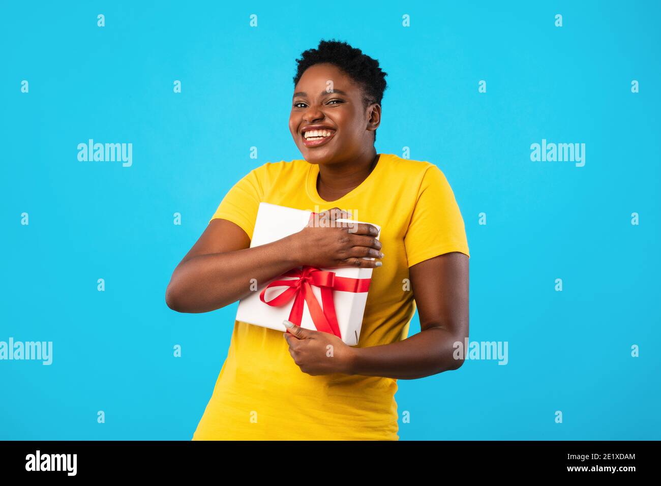 Joyful Plus-Size Black Woman Hugging Gift Box Over Blue Background ...