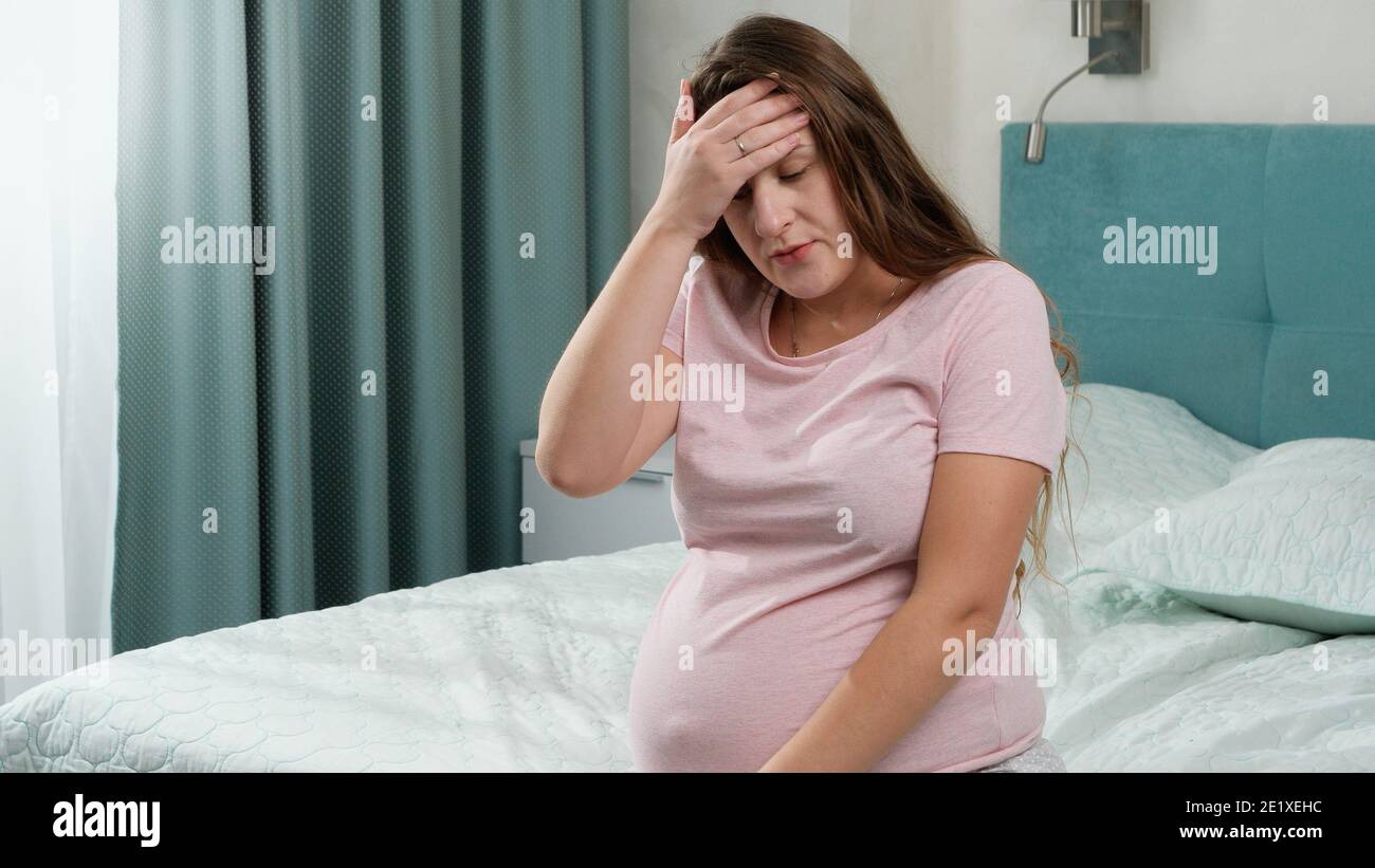 Portrait of upset pregnant woman feeling lonely and upset sitting on ...