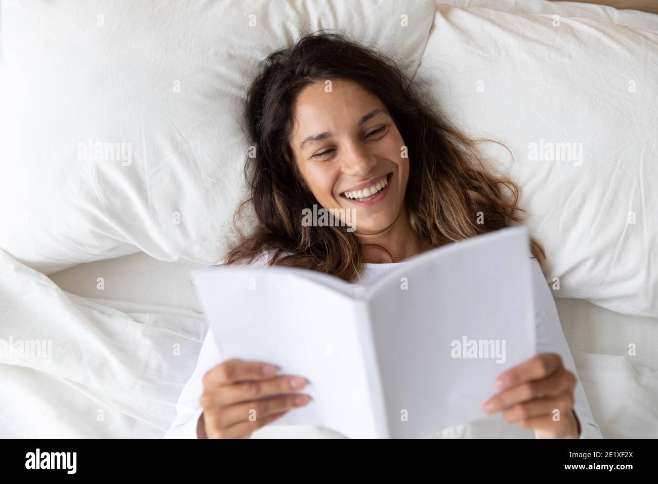 Top view smiling woman reading book, resting in bed Stock Photo - Alamy