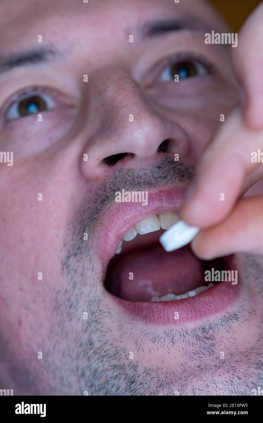 Extreme closeup man face taking white pill, mouth view swallowing pills ...